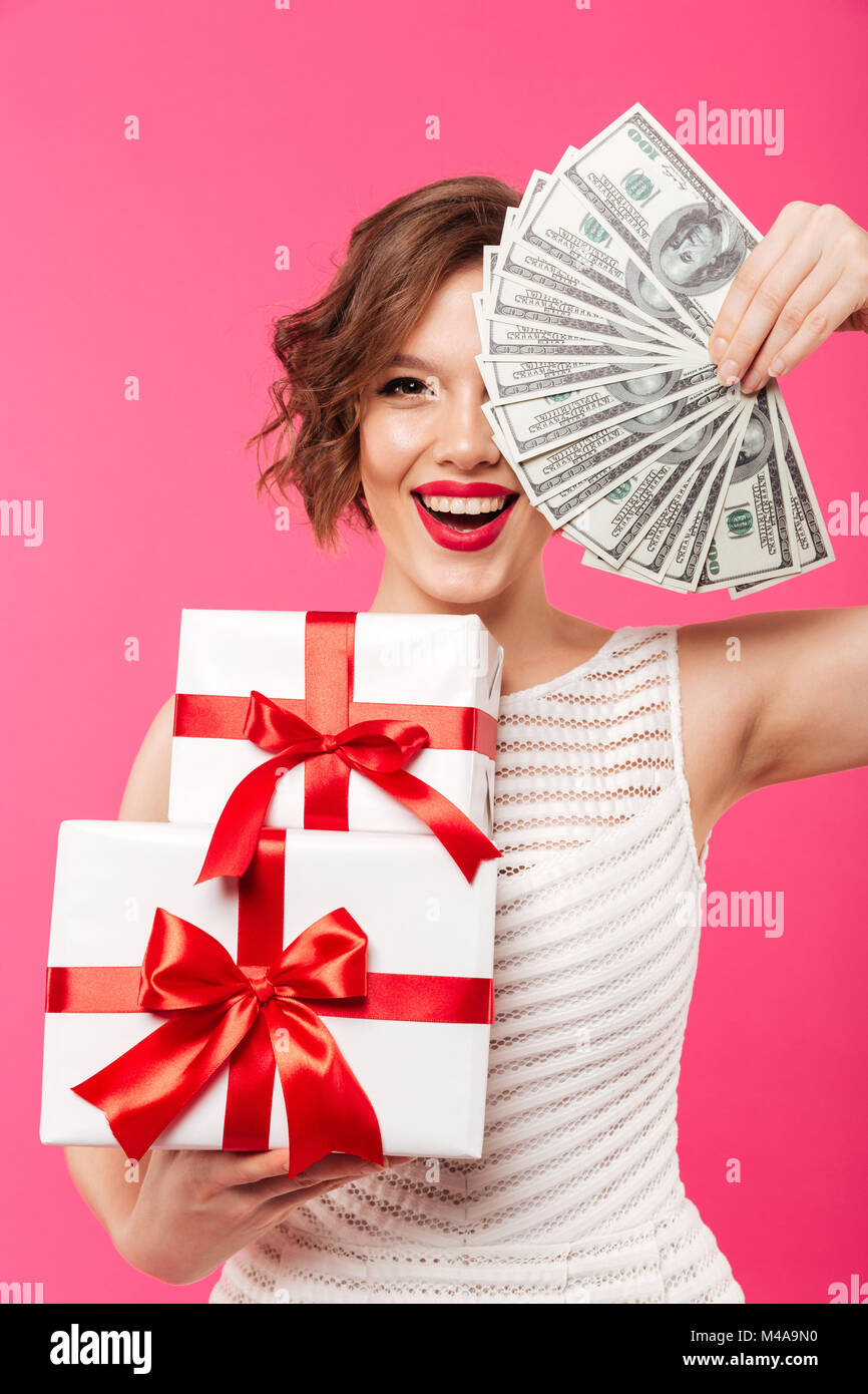 Portrait of a happy girl dressed in dress holding stack of gift boxes ...