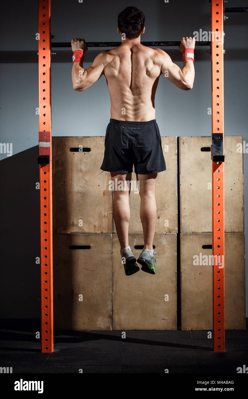 attractive young male adults doing pull ups on bar in cross fit ...