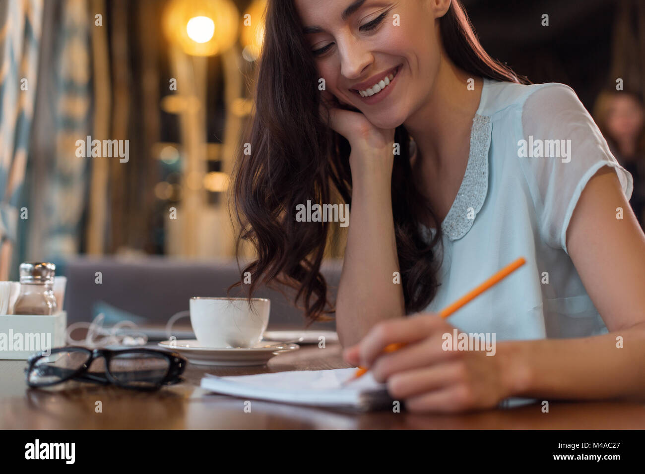 Nice musing woman writing down agenda Stock Photo - Alamy