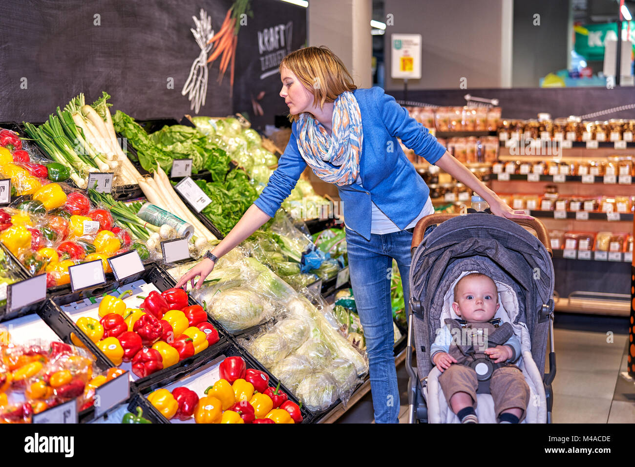 Woman in blue jacket and jeans choosing vegetables Stock Photo - Alamy