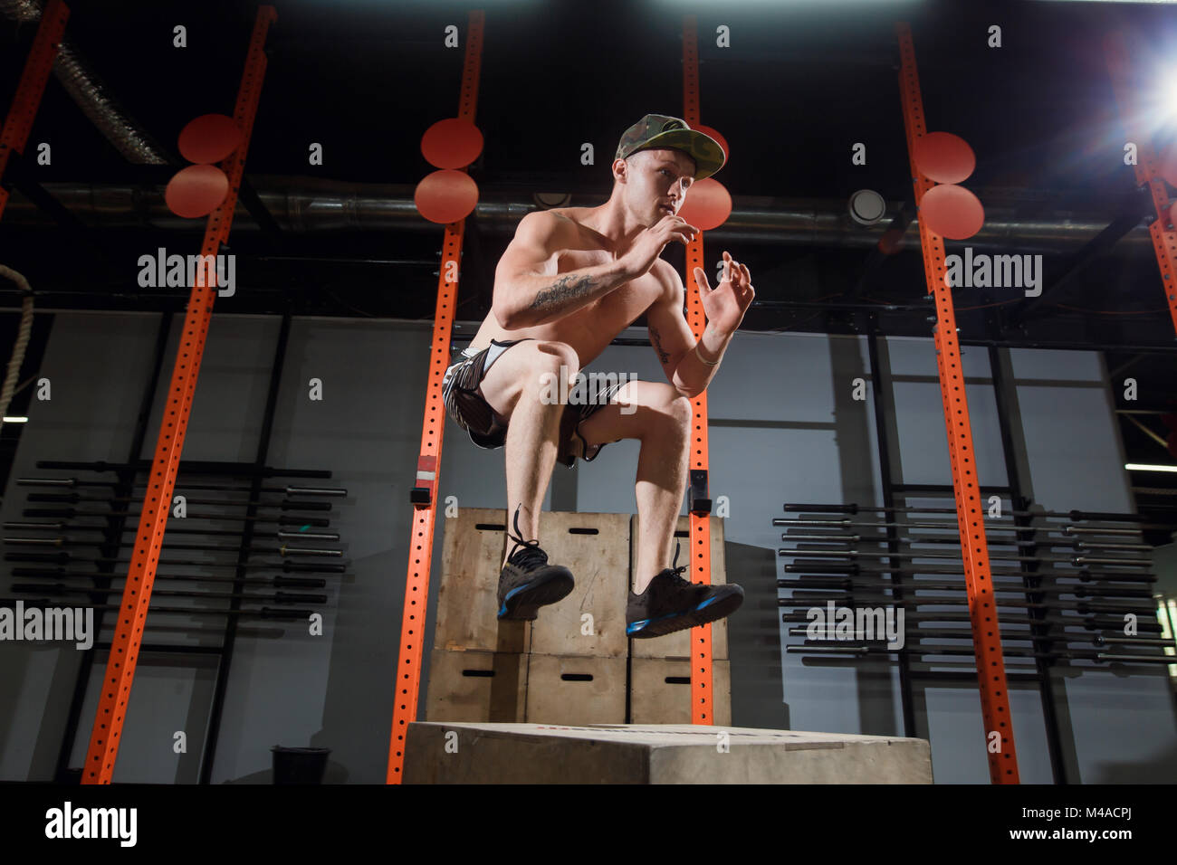 Low angle view of young male athlete box jumping at a cross fit gym ...
