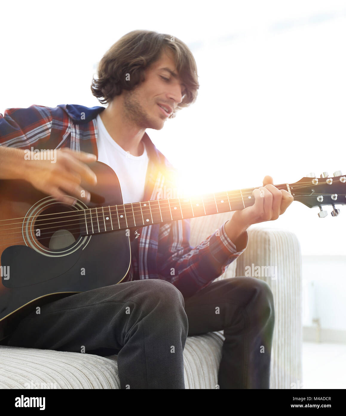 guy sings a song and plays guitar sitting on the couch Stock Photo - Alamy