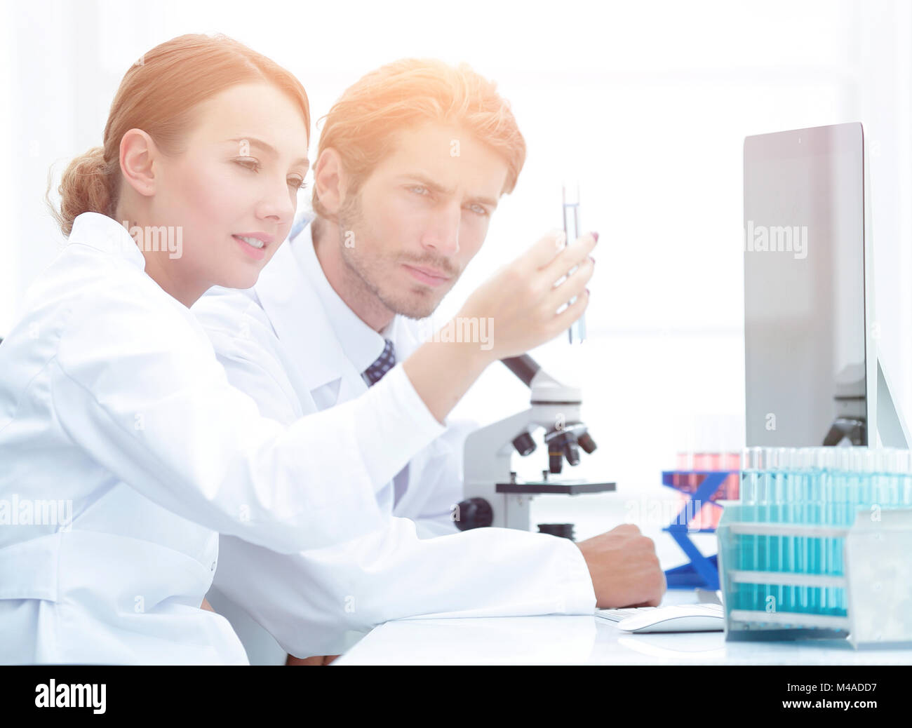 Woman looking at test tubes with colorful liquids Stock Photo - Alamy