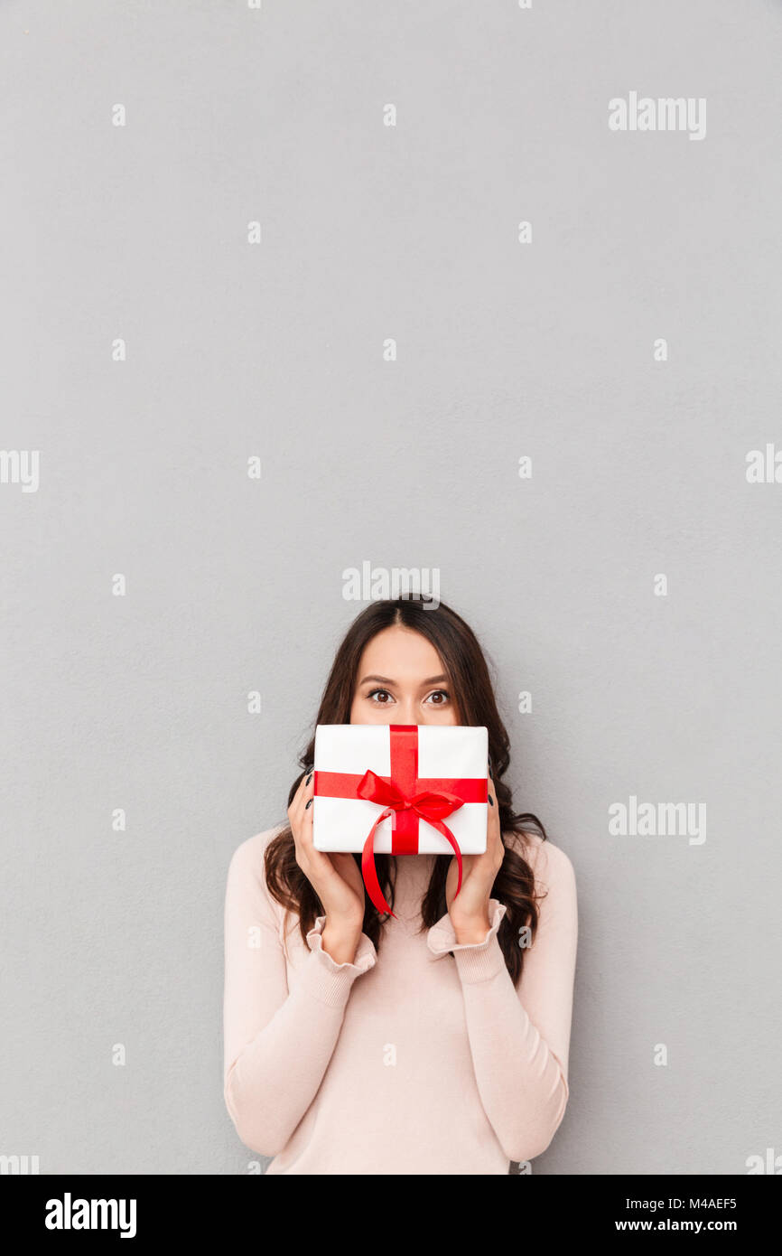 Pleased female covering her face with festive box gift-wrapped, being ...