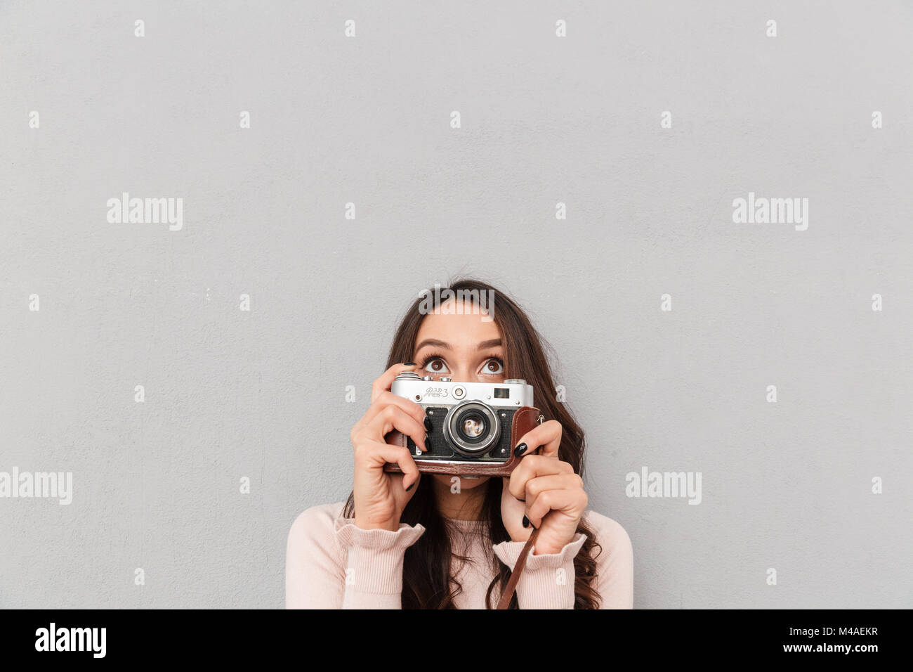 Portrait of joyful female photographer having fun, while taking photos ...