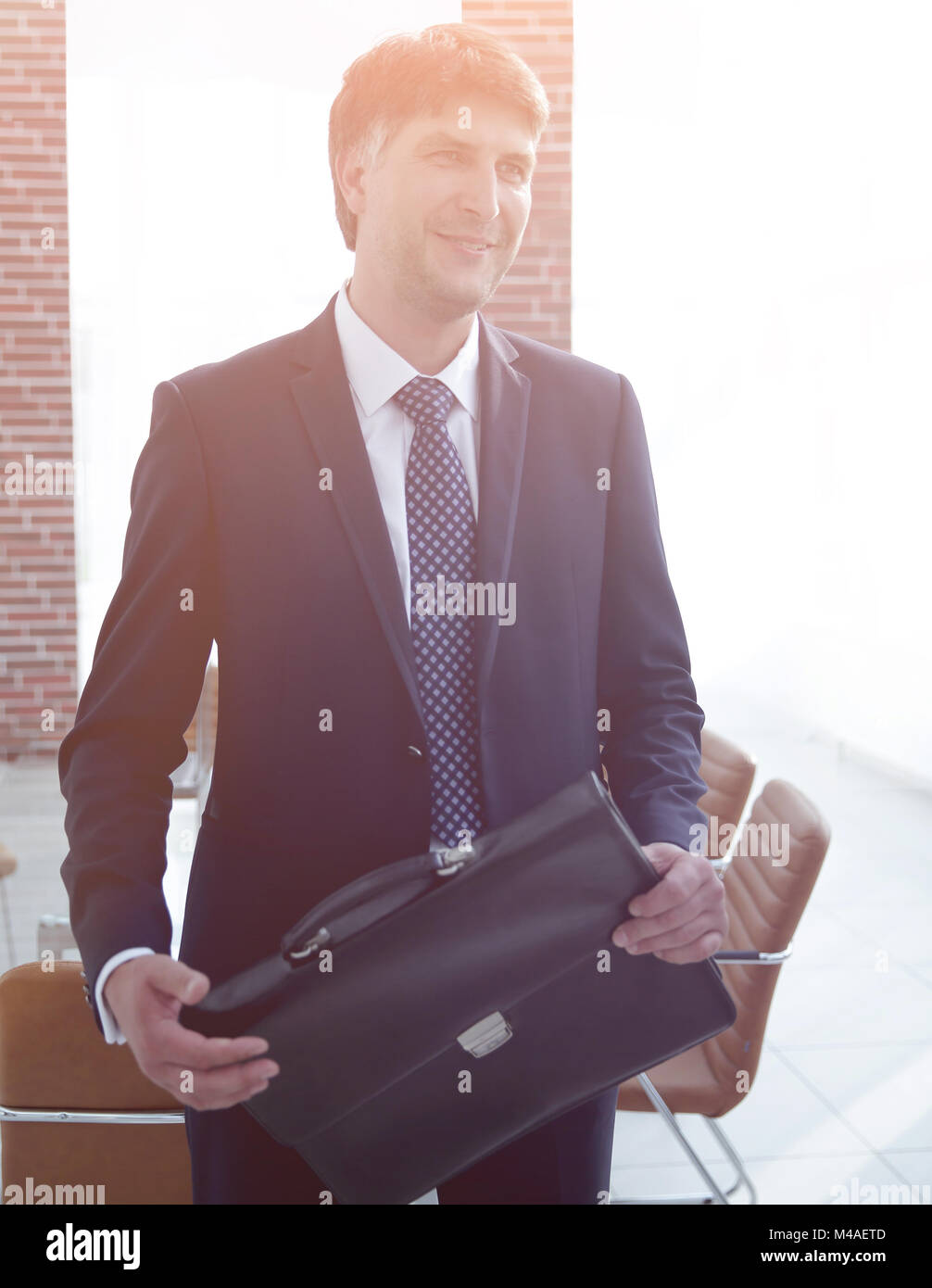 Business man with briefcase standing on office background Stock Photo ...