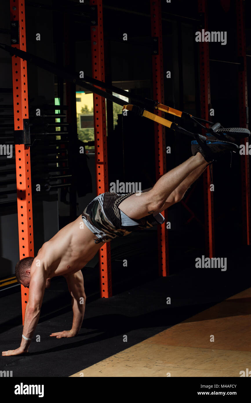 Cross fit fitness TRX training exercises at gym man side push-up ...