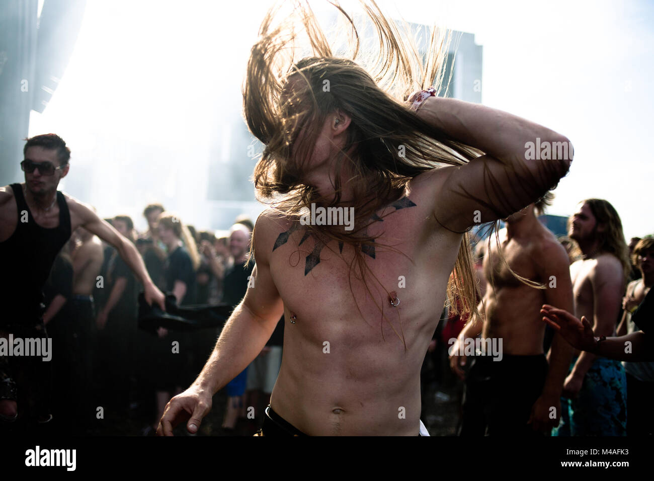 A long haired heavy metal fan with tattoo and body piercing is dancing ...