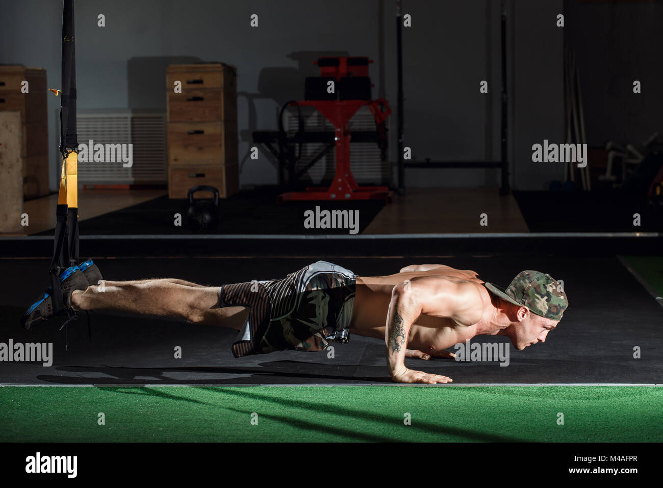 Cross fit fitness TRX training exercises at gym man side push-up ...