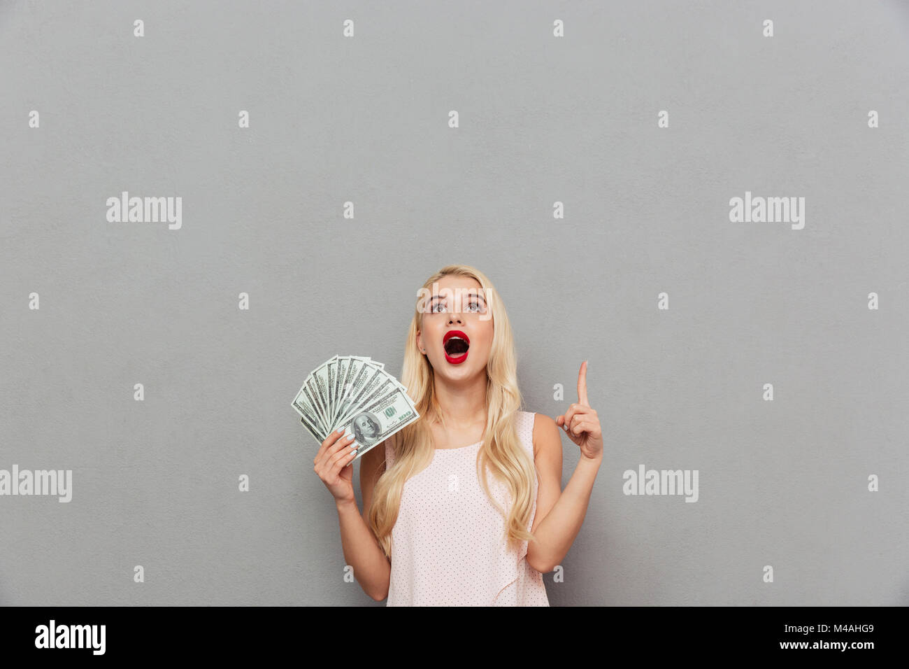 Portrait of an excited woman holding bunch of money banknotes and ...