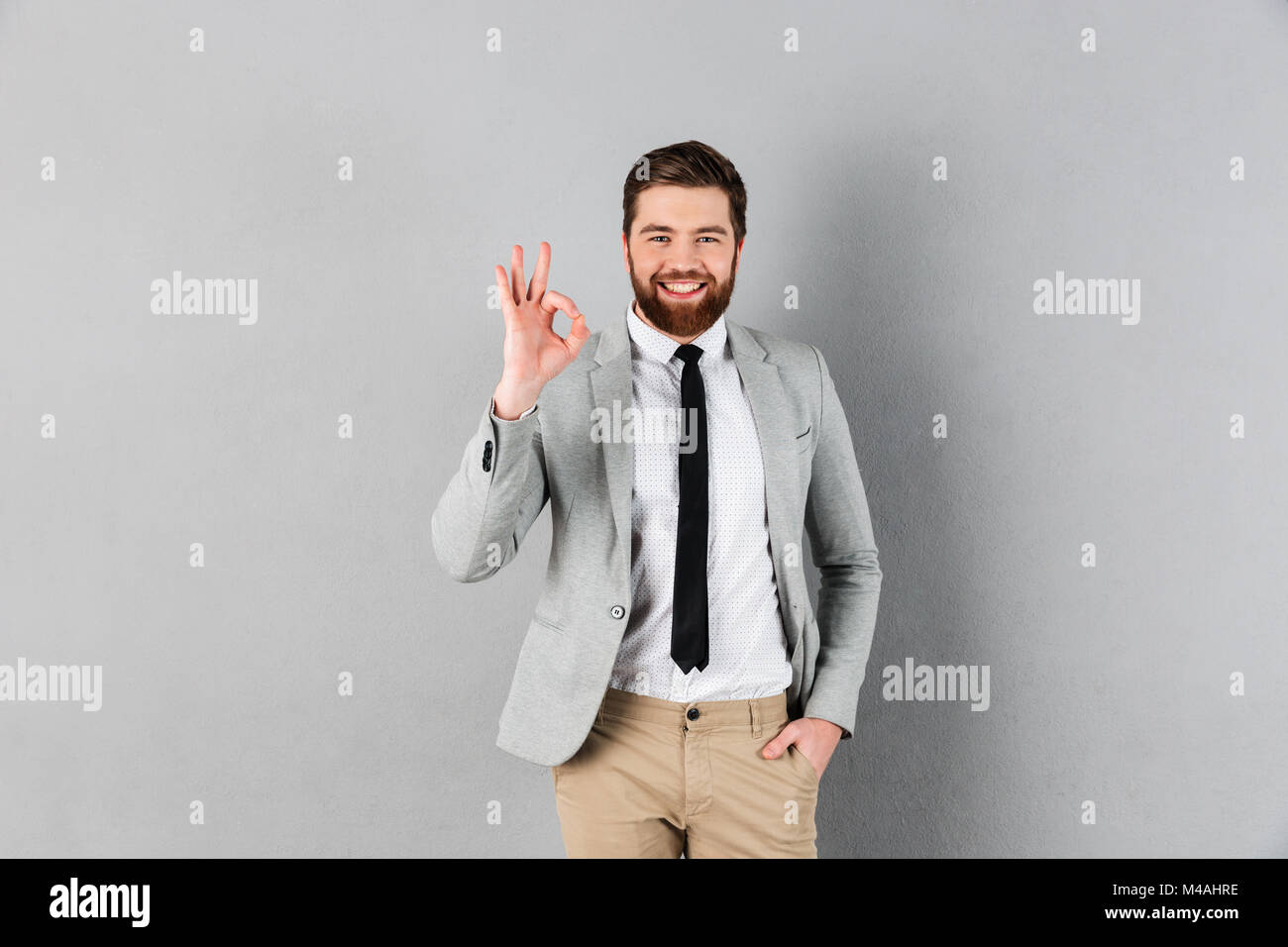 Portrait of a smiling businessman dressed in suit showing ok gesture ...