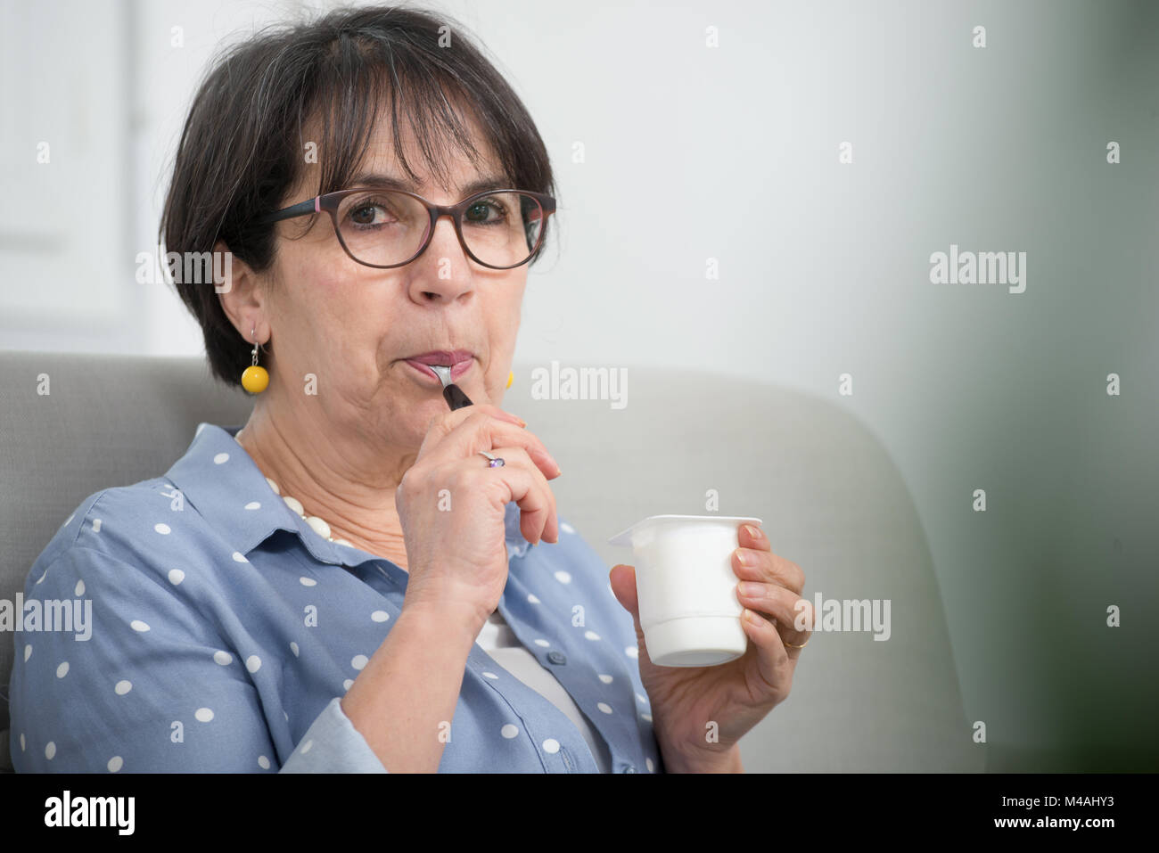 pretty mature woman eating a yogurt at home Stock Photo - Alamy