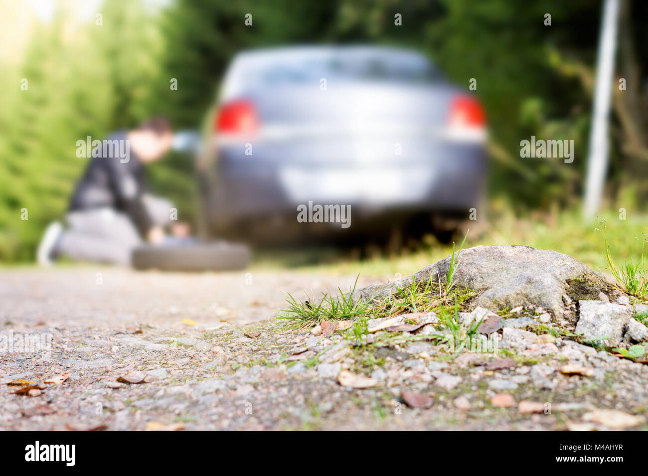 Man changing new spare wheel after vehicle hit rock on countryside sand ...