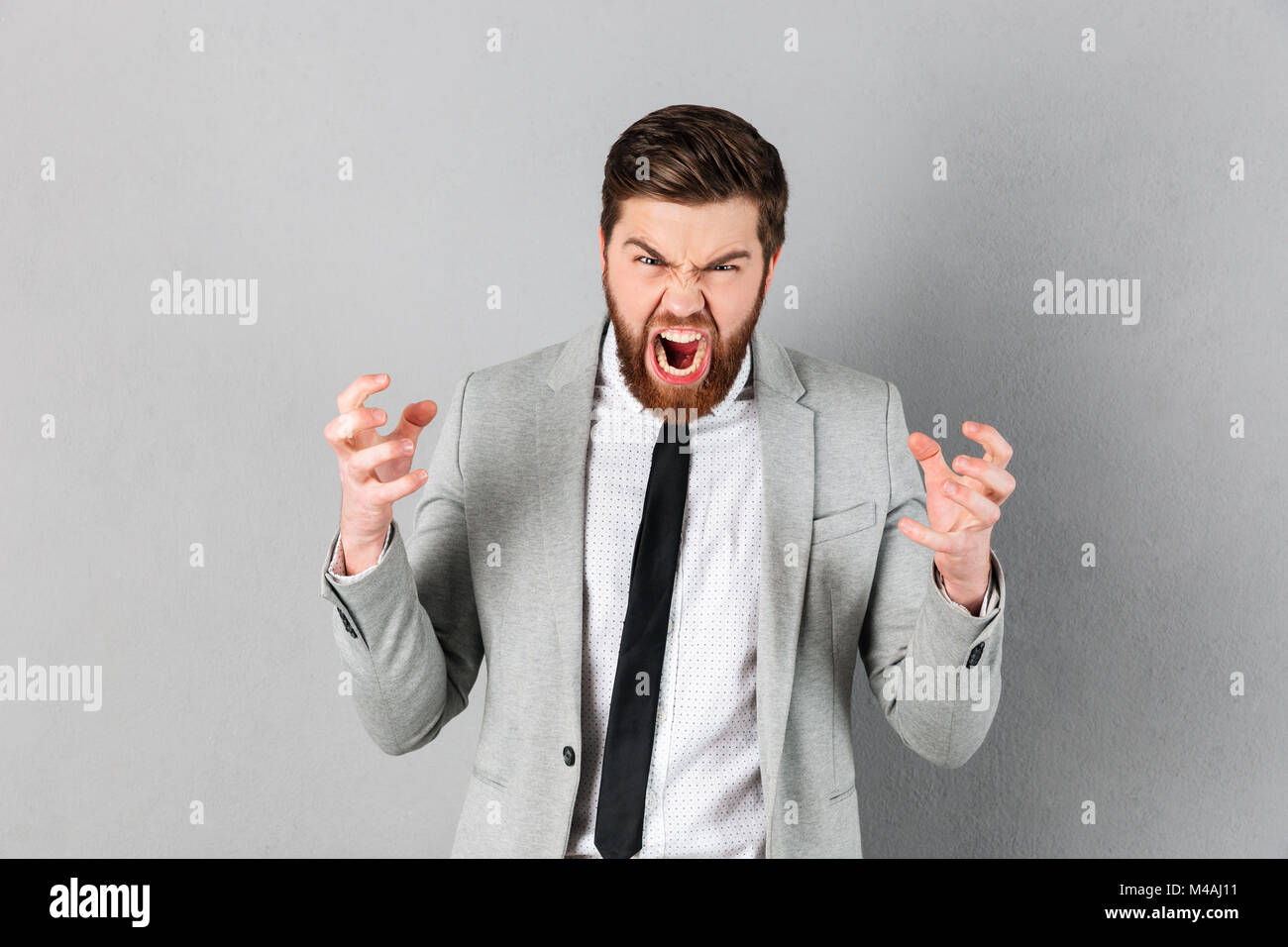 Portrait of a furious businessman dressed in suit screaming and ...