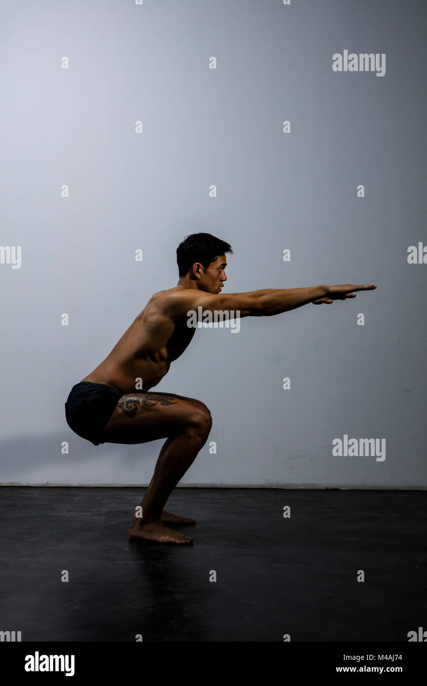 Asian fitness model performing squatting exercises. Profile Stock Photo ...