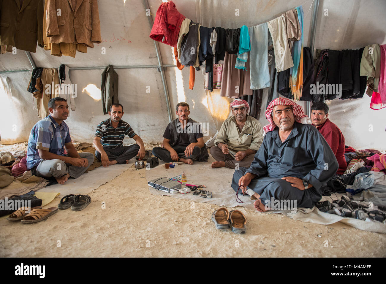 A group of Syrian refugee men sitting inside a tent in the Suruç camp ...