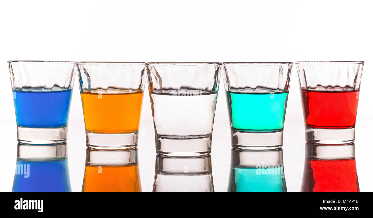 still life of five small glasses with colored beverages in a white ...