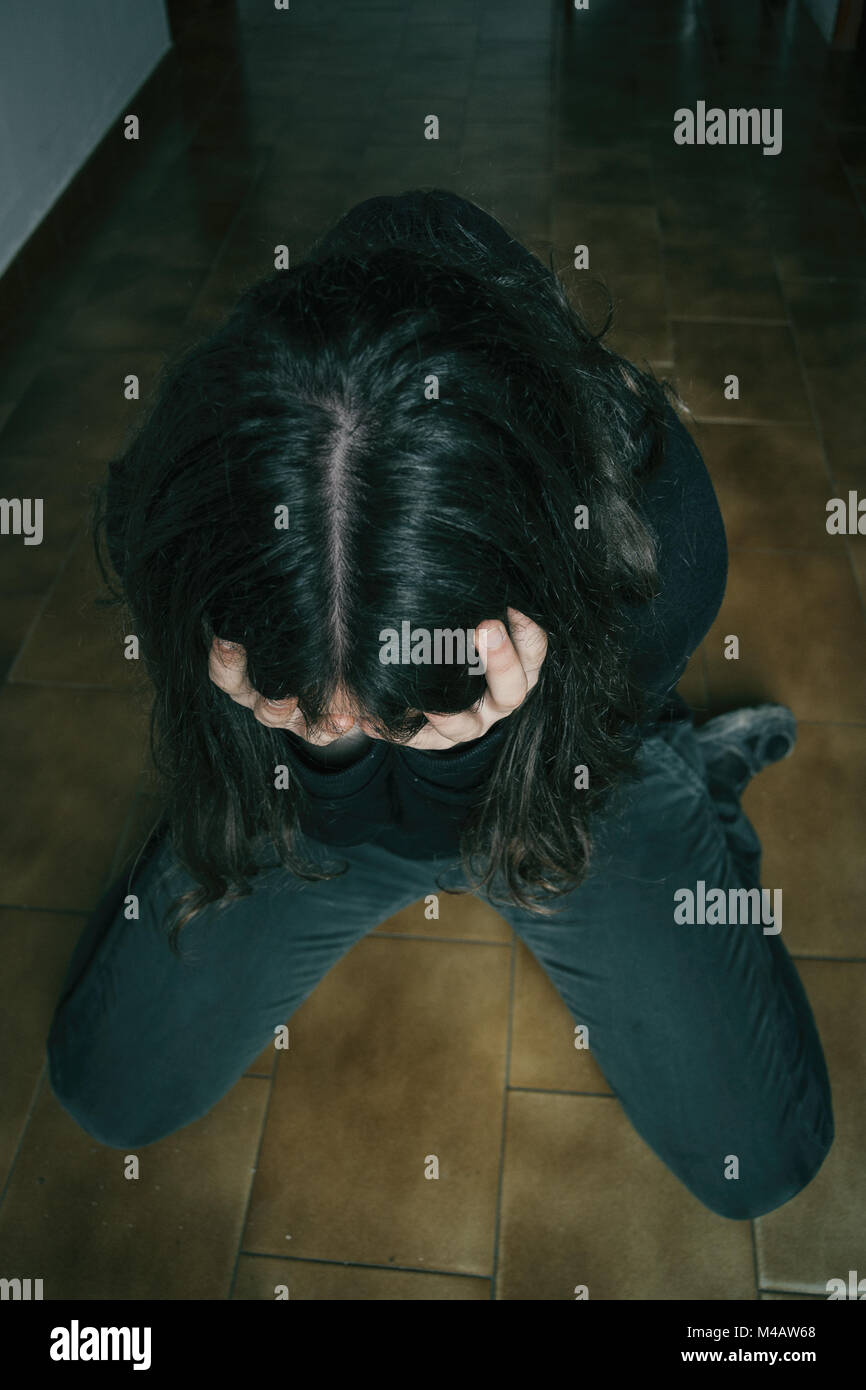 sad girl with long hair kneeling on the floor covering her face Stock ...