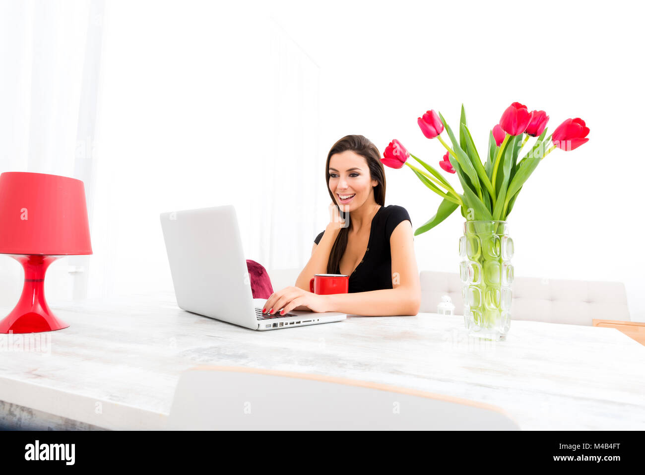 Young beautiful woman smiling while using a Laptop at home Stock Photo ...