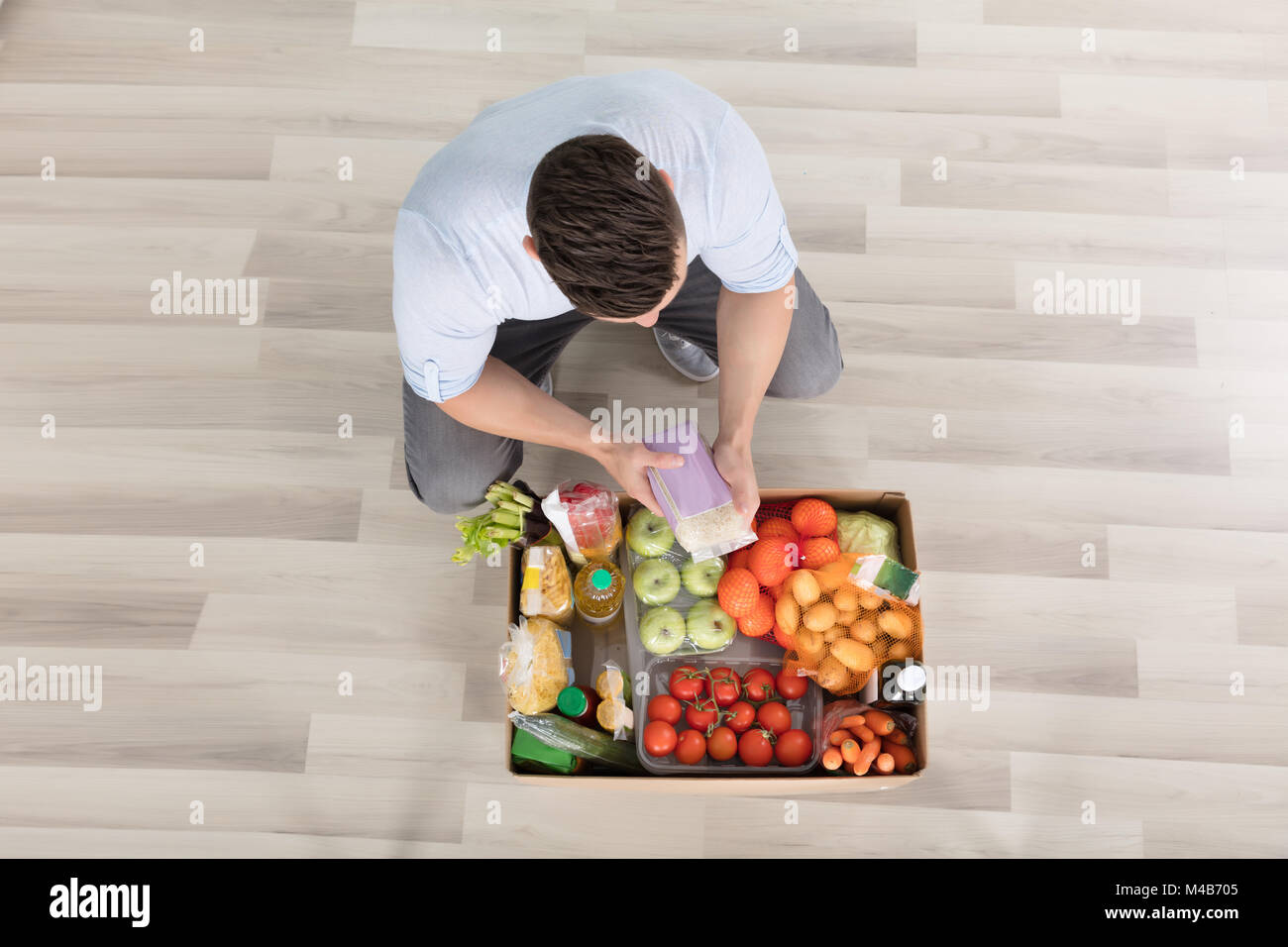 Young Man Checking The Groceries In The Box At Home Stock Photo - Alamy