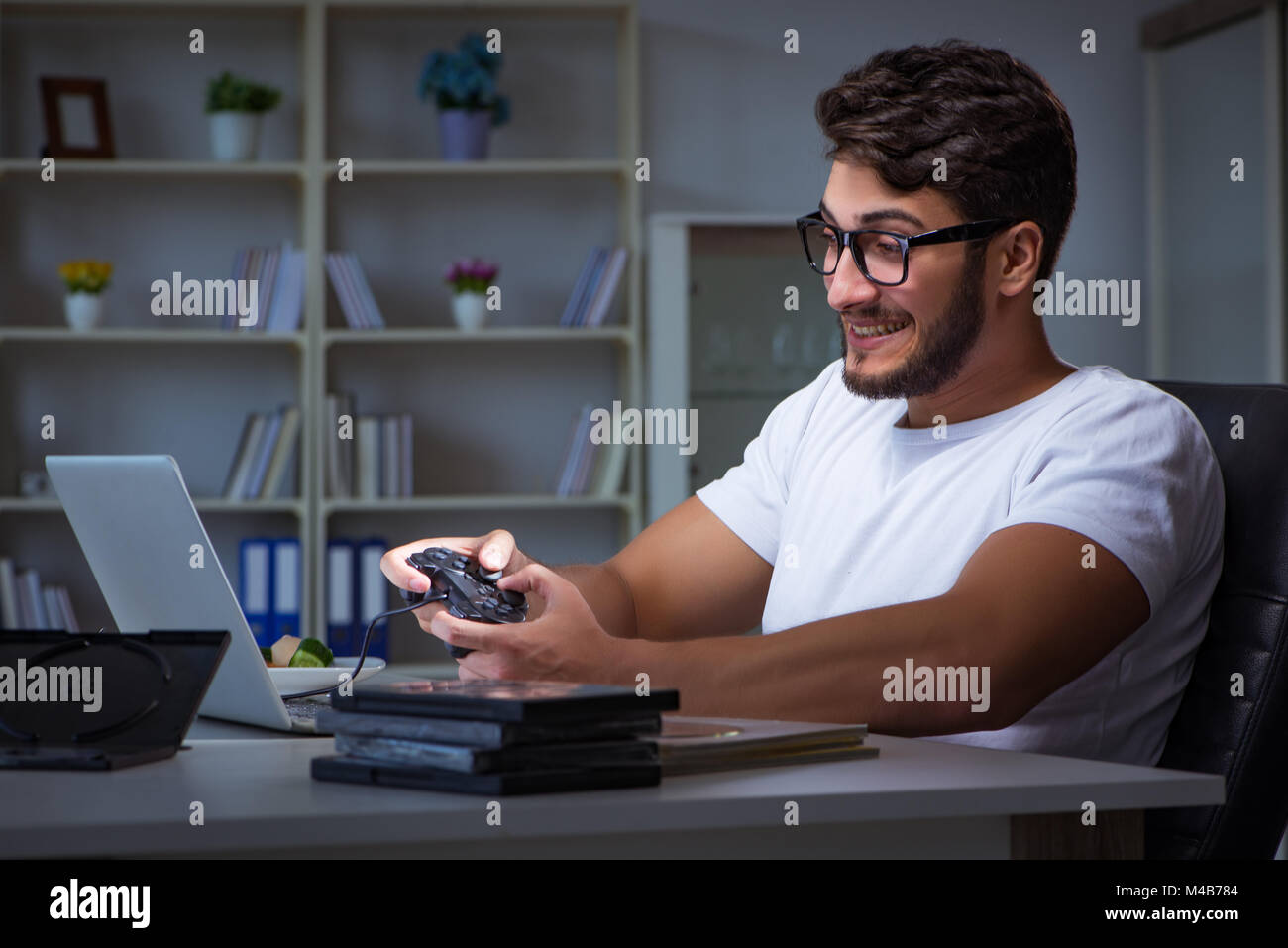 Young man playing games long hours late in the office Stock Photo - Alamy