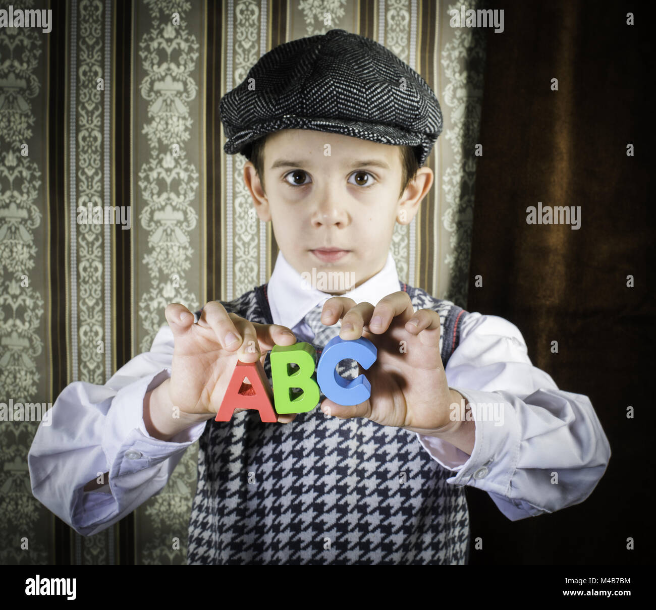 Child in vintage clothes hold letters a b c Stock Photo - Alamy