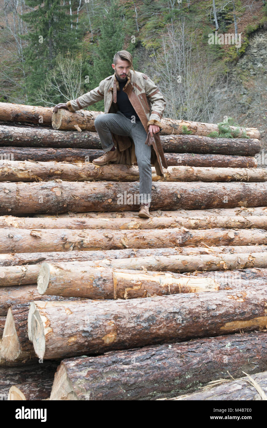 Young men on logs in the forest. Pine trees Stock Photo - Alamy