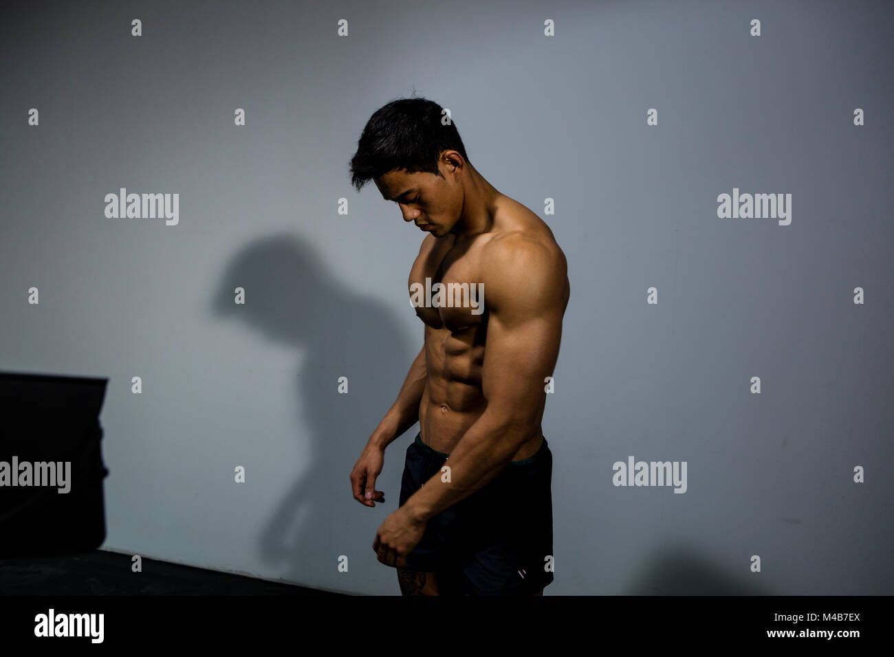 A fitness model looks down towards his own muscles. Profile. Medium ...