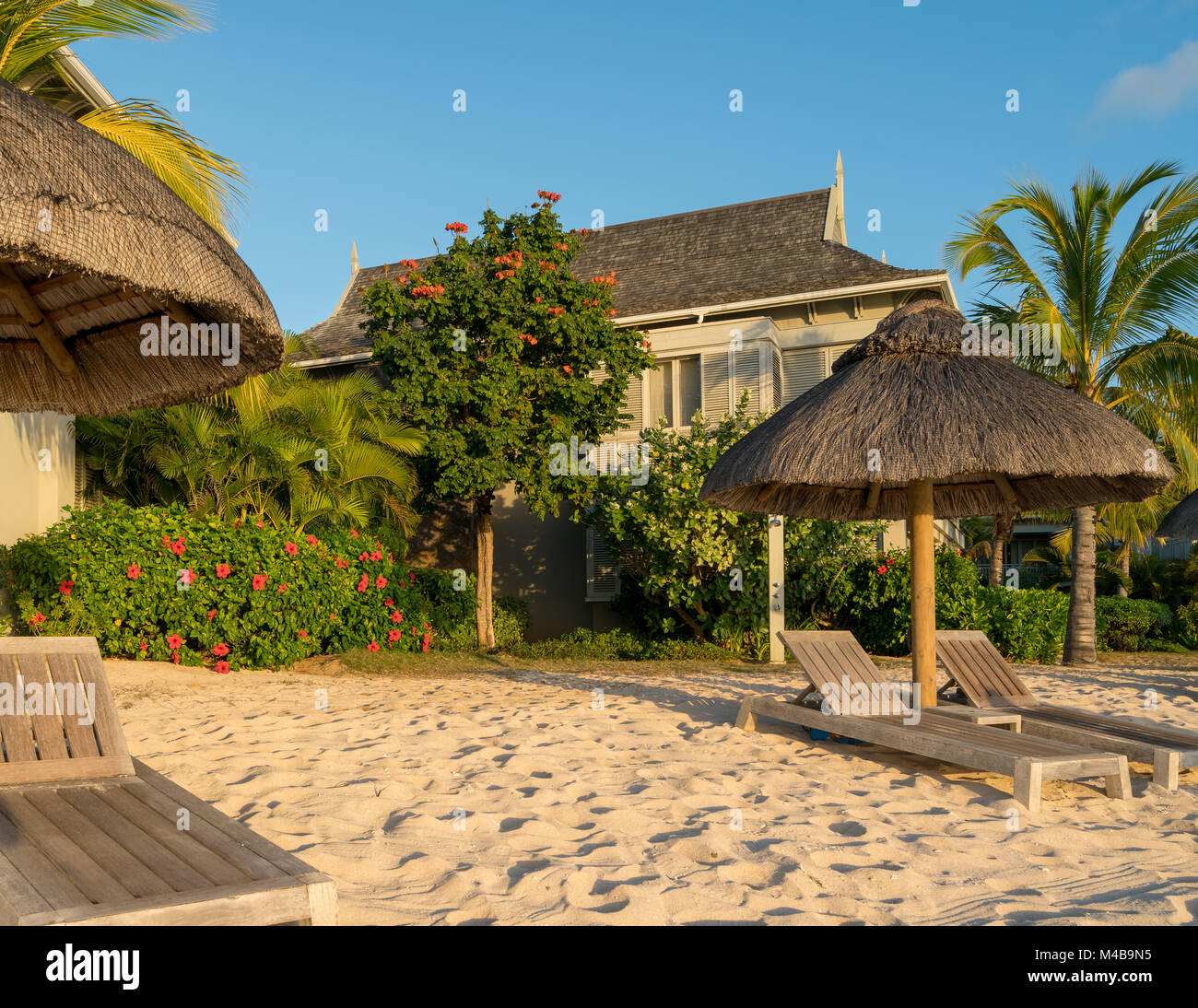 Beach at Mauritius island with wooden parasol,garden and bungalow ...