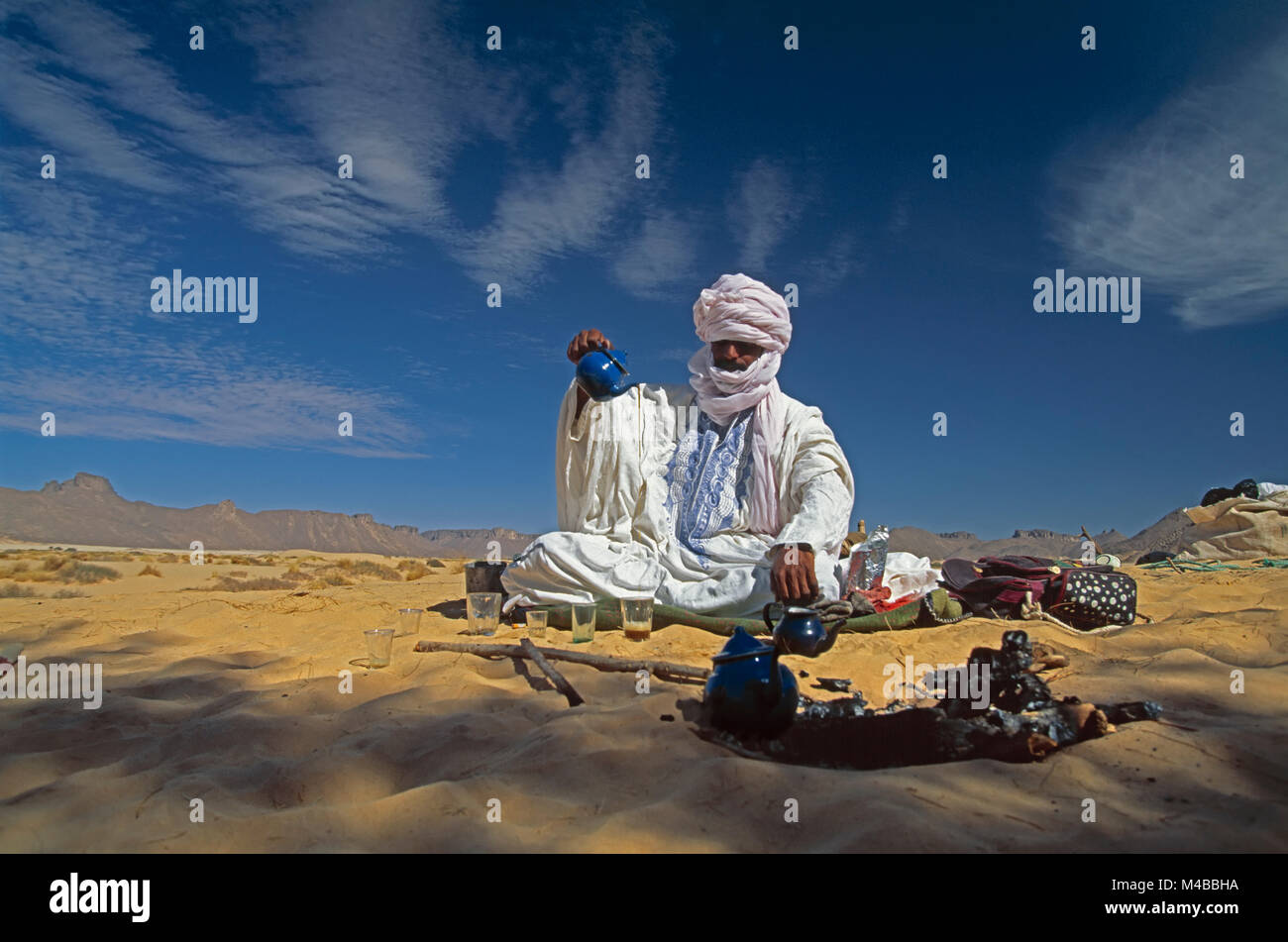Algeria. Near Djanet. Sahara desert. Man of Tuareg tribe making tea ...