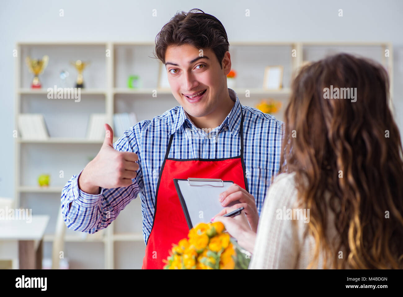 Flower shop assistant selling flowers to female customer Stock Photo ...