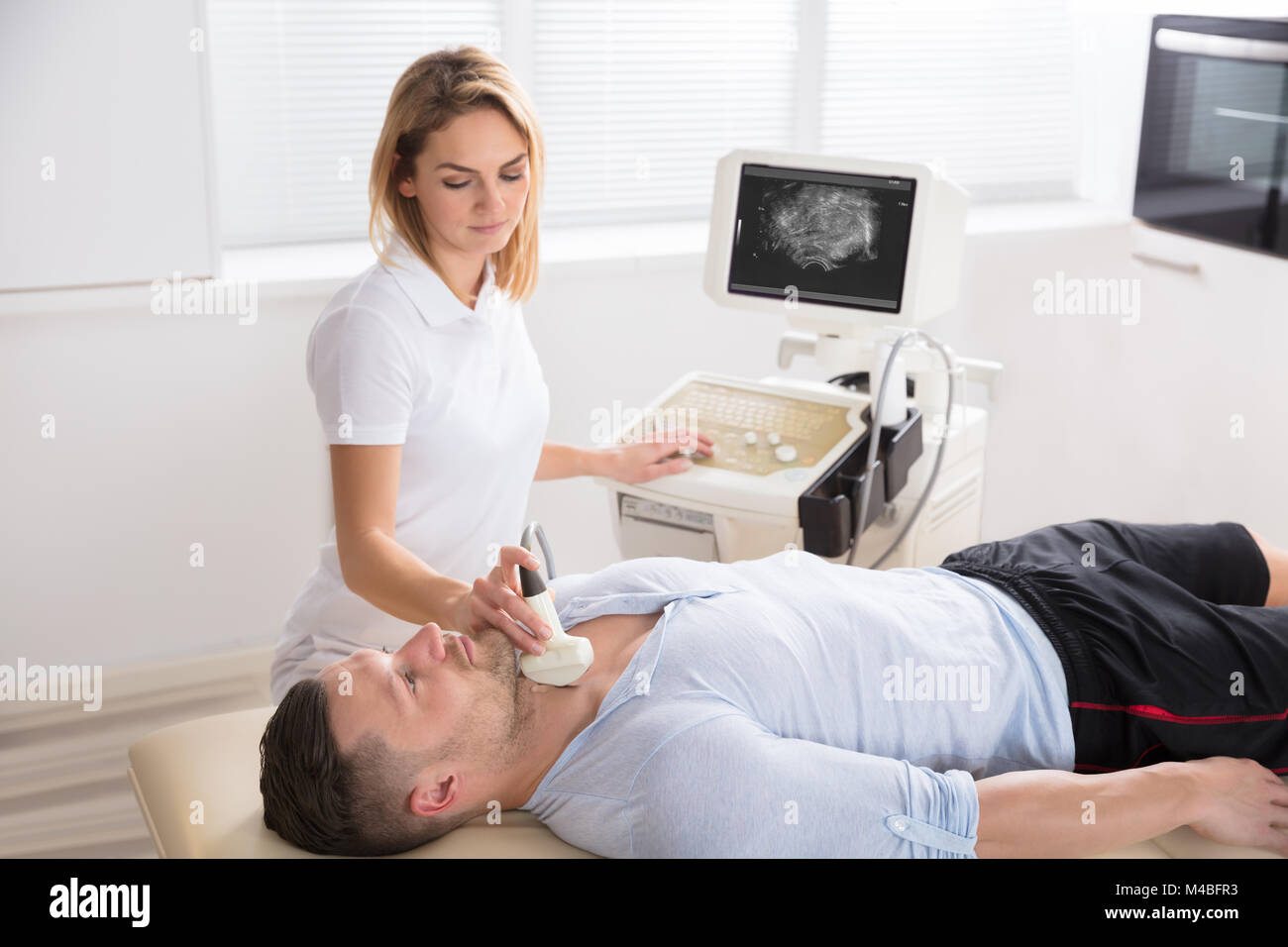 Young Female Doctor Performing Thyroid Ultrasound Test On Male Patient ...