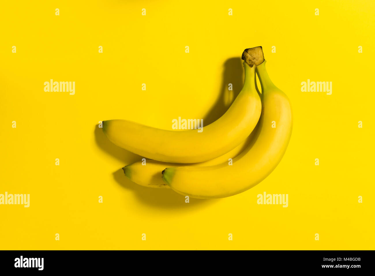 Three bananas on a yellow background still life image Stock Photo - Alamy
