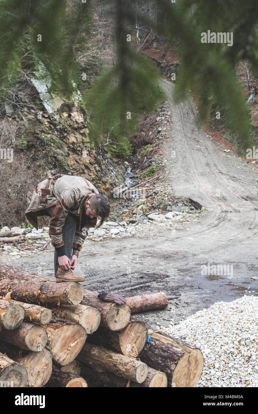 Young men on logs in the forest. Pine trees Stock Photo - Alamy