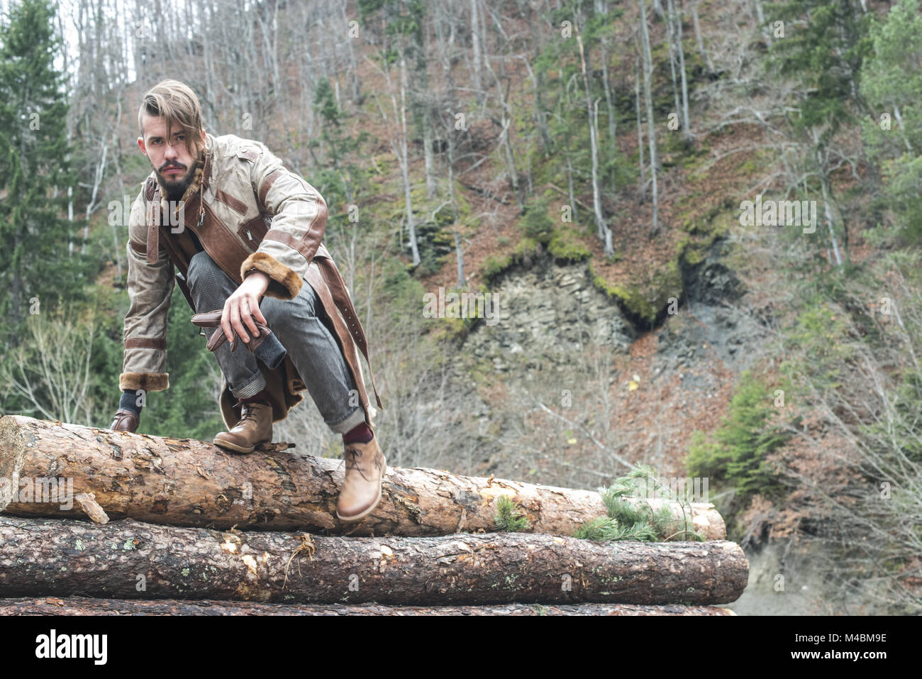 Young men on logs in the forest. Pine trees Stock Photo - Alamy