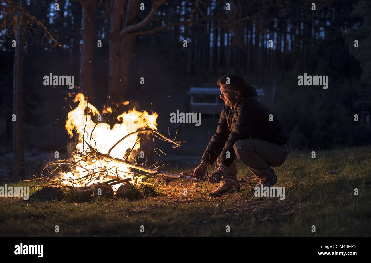 Man lights a fire in the fireplace in nature Stock Photo - Alamy