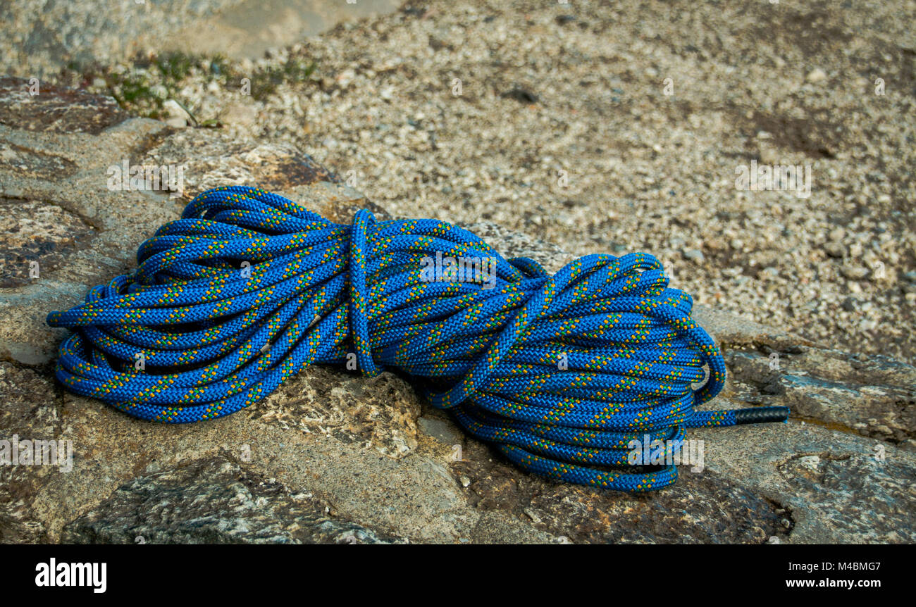 Blue climbing rope laying folded on a rock Stock Photo - Alamy