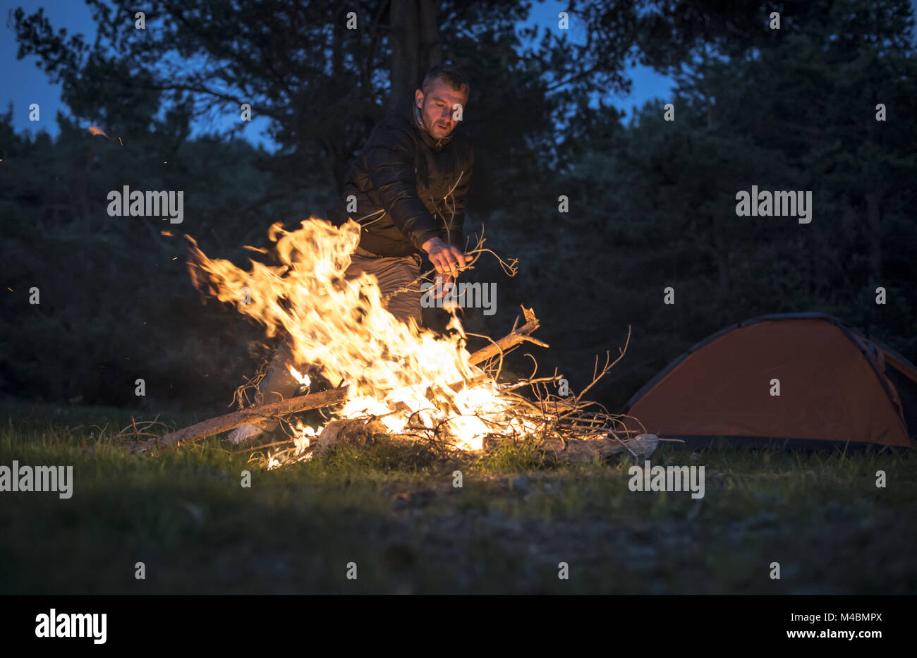 Man lights a fire in the fireplace in nature Stock Photo - Alamy