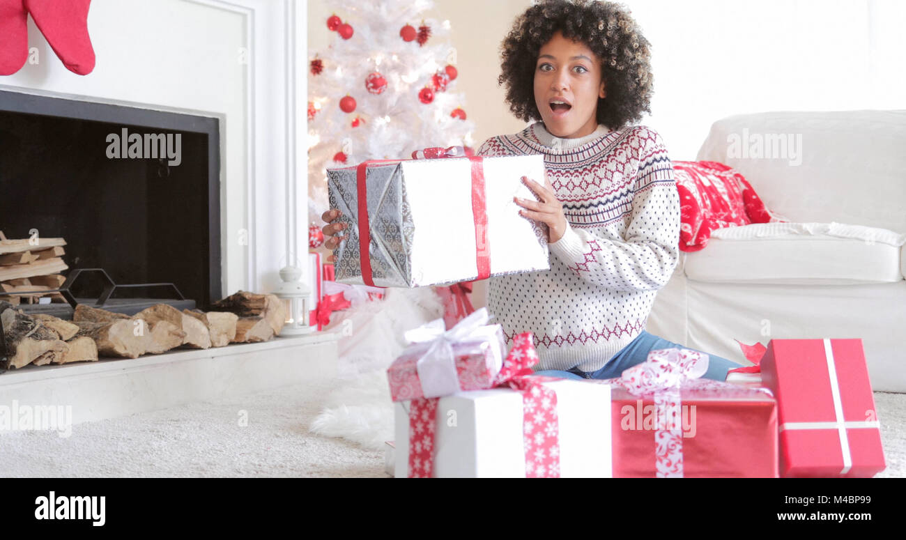 Surprised woman holding a large Christmas gift Stock Photo - Alamy