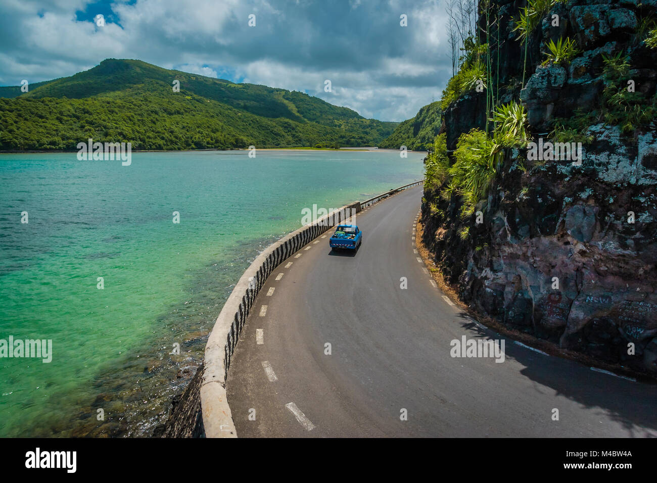 A vehicle on a stretch of a littoral road along a bay at Maconde ...
