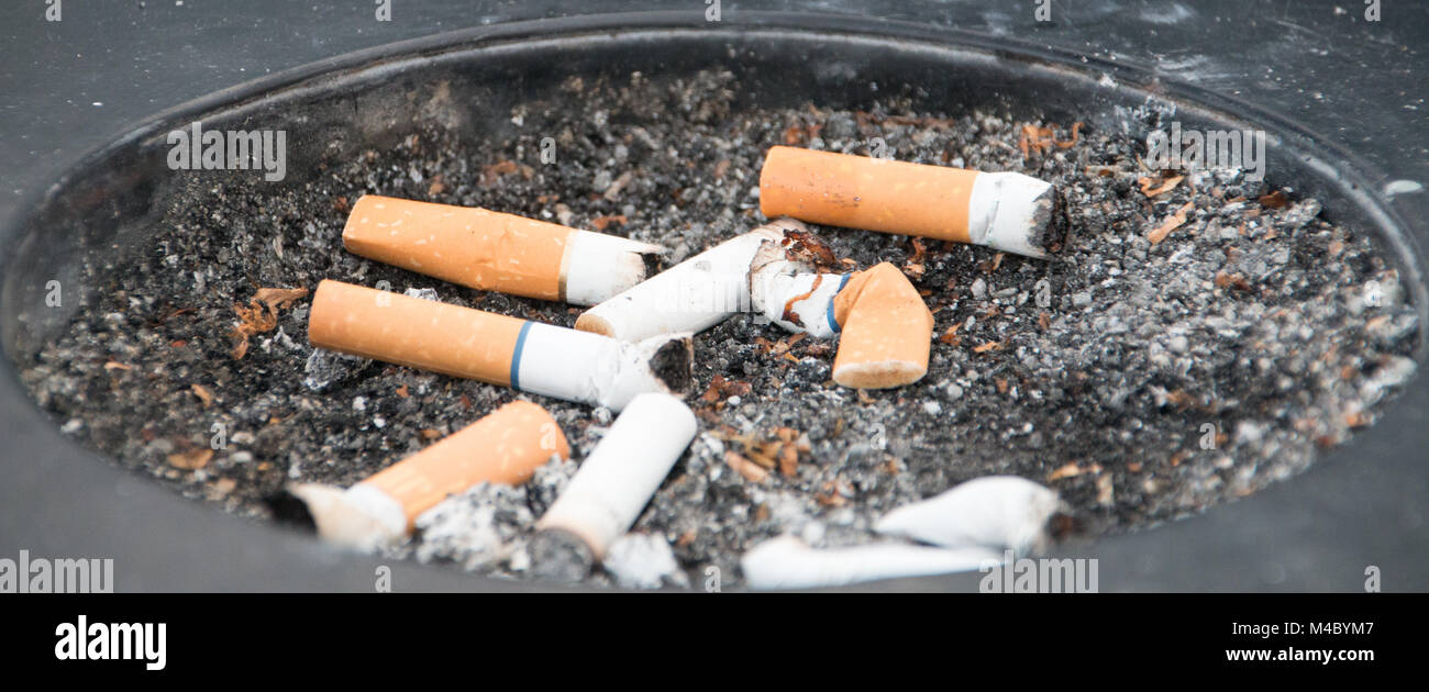 Dirty black ashtray with smoked cigarettes Stock Photo - Alamy