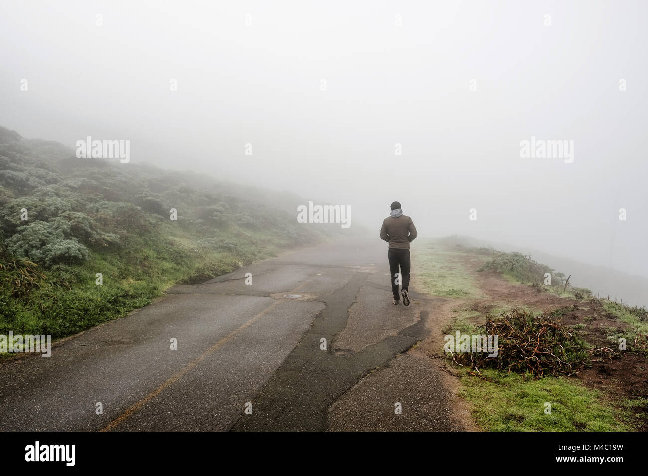 Lone man walking through the white fog Stock Photo - Alamy