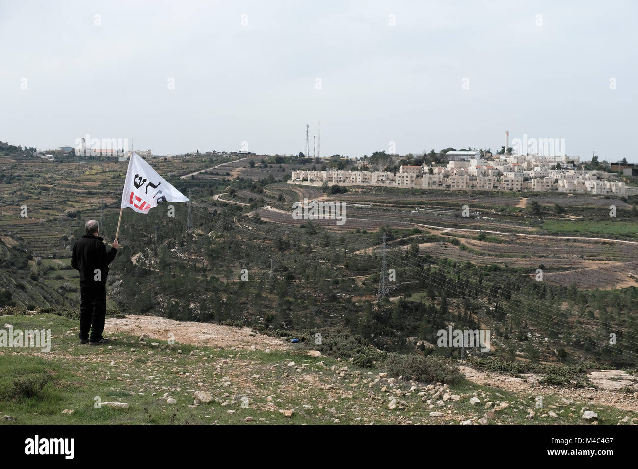 A left-wing activist stands with the flag of the Peace Now movement and ...