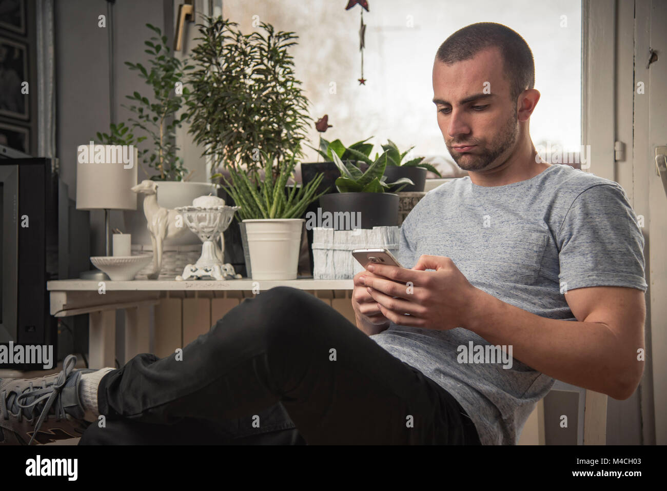 Young an using his cell phone at home Stock Photo - Alamy