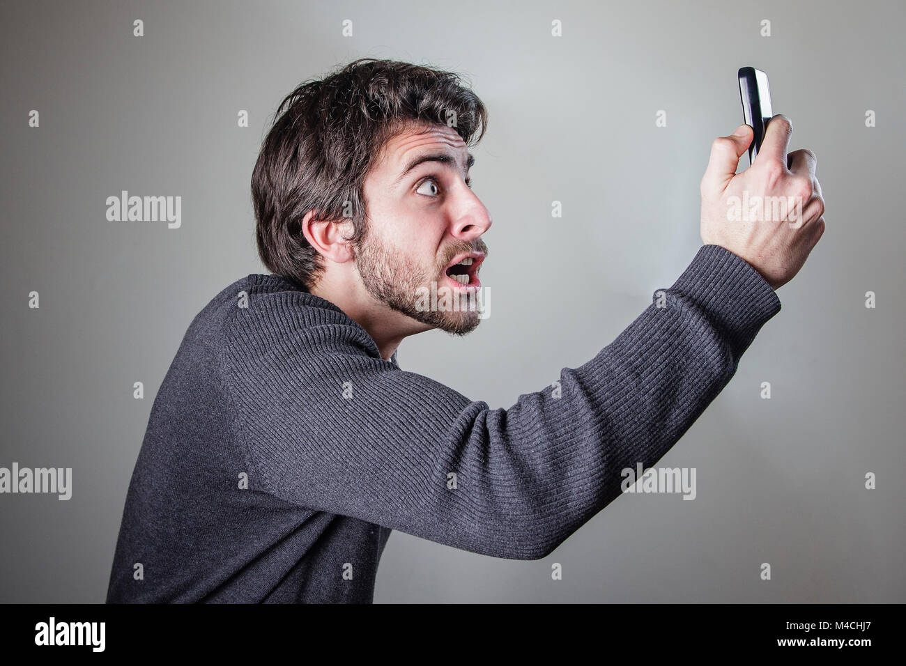 Outraged and angry man yelling at his phone Stock Photo - Alamy