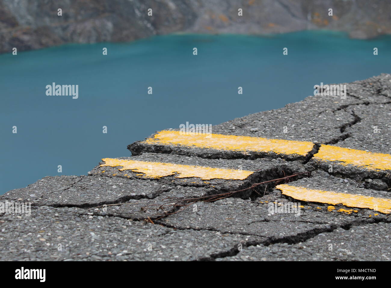 Destroyed road due to a mining collapse overlooking a green-blue lake ...