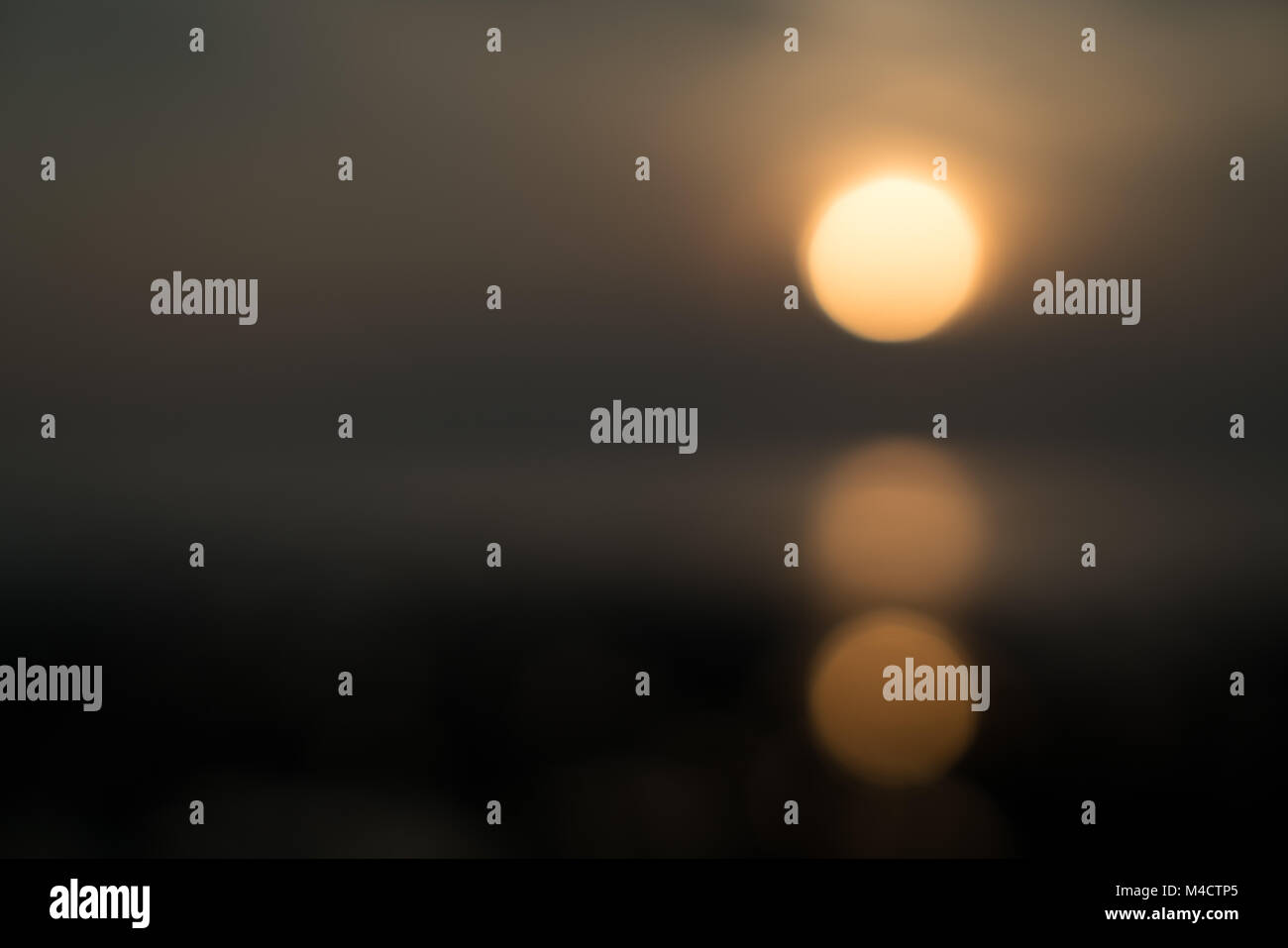 Background image defocused abstract rising sun above horizon refelected ...