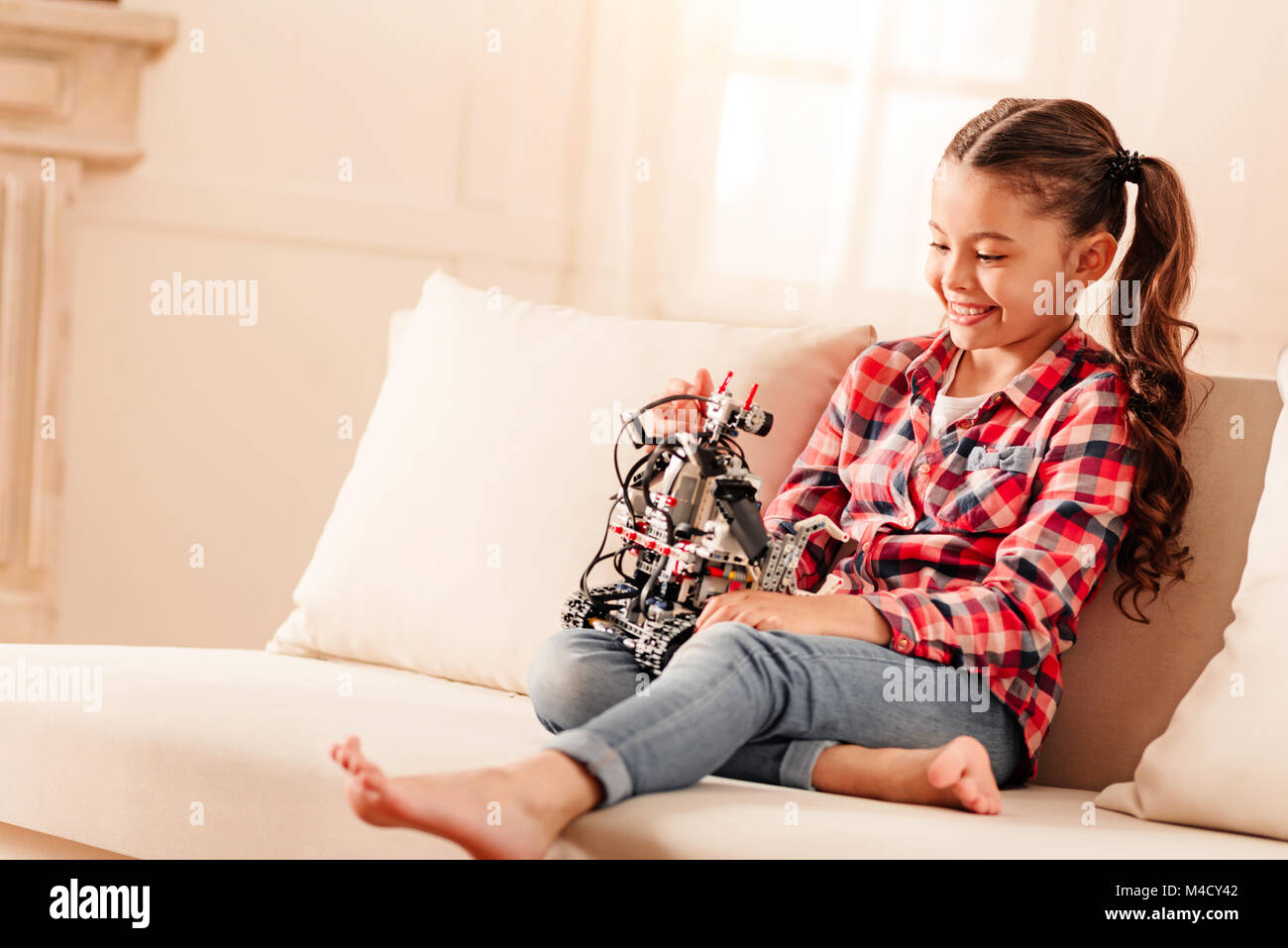 Little girl grinning broadly while having fun with robot toy Stock ...