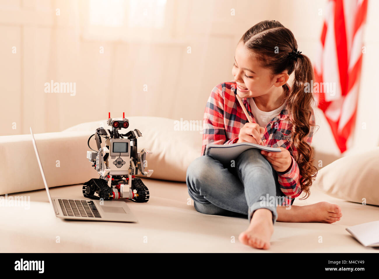 Smart child writing her essay on robotic machines Stock Photo - Alamy