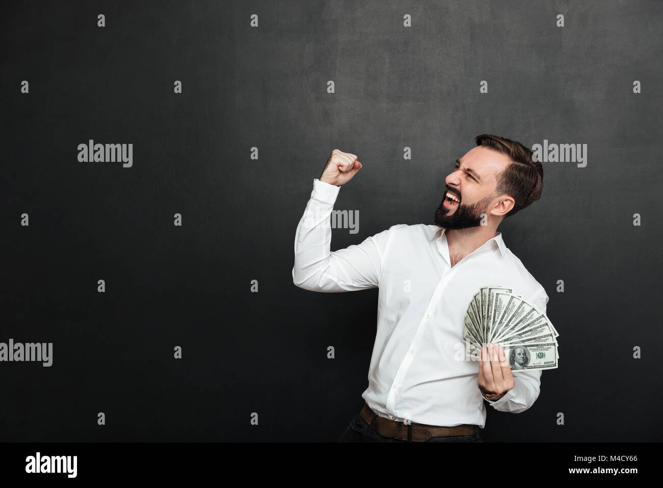 Portrait of successful guy in white shirt rejoicing like winner with ...